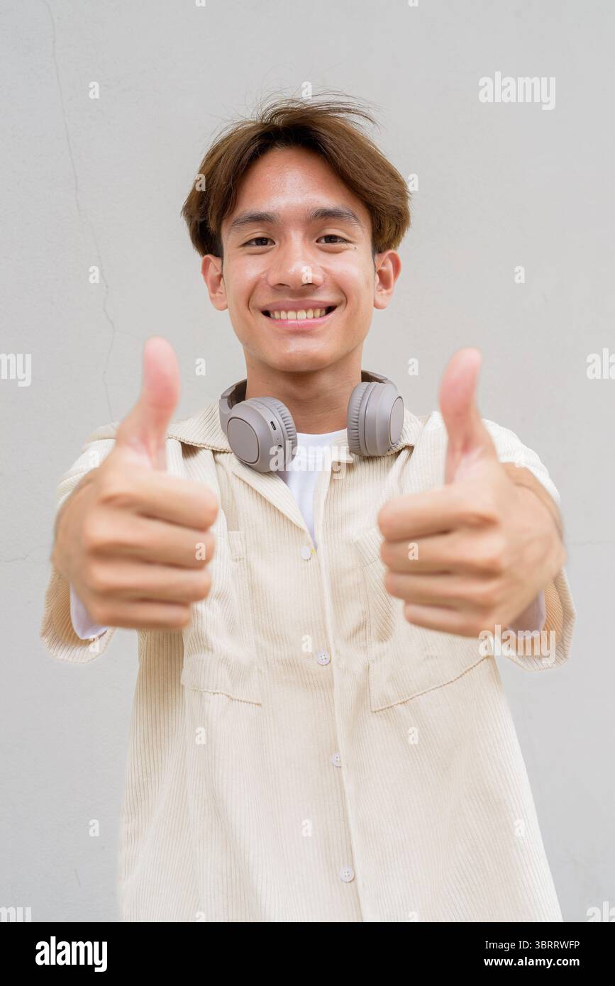 Non binary cute Asian young gay man portrait against plain background ...