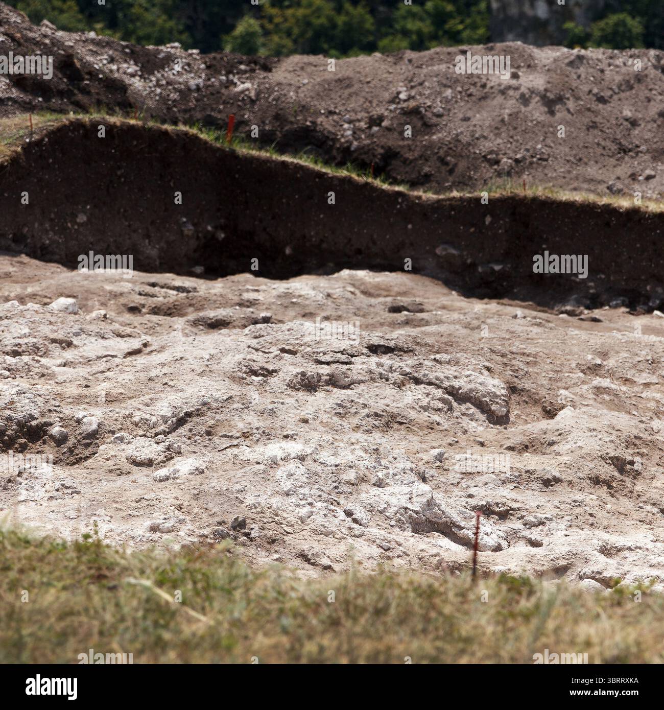 Exposed archaeological dig site showing soil layers and chalky surface ...