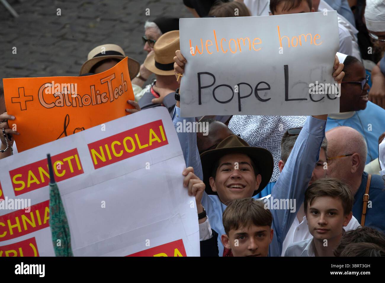 A faithful young boy is seen holding a placard that reads "Welcome Home ...