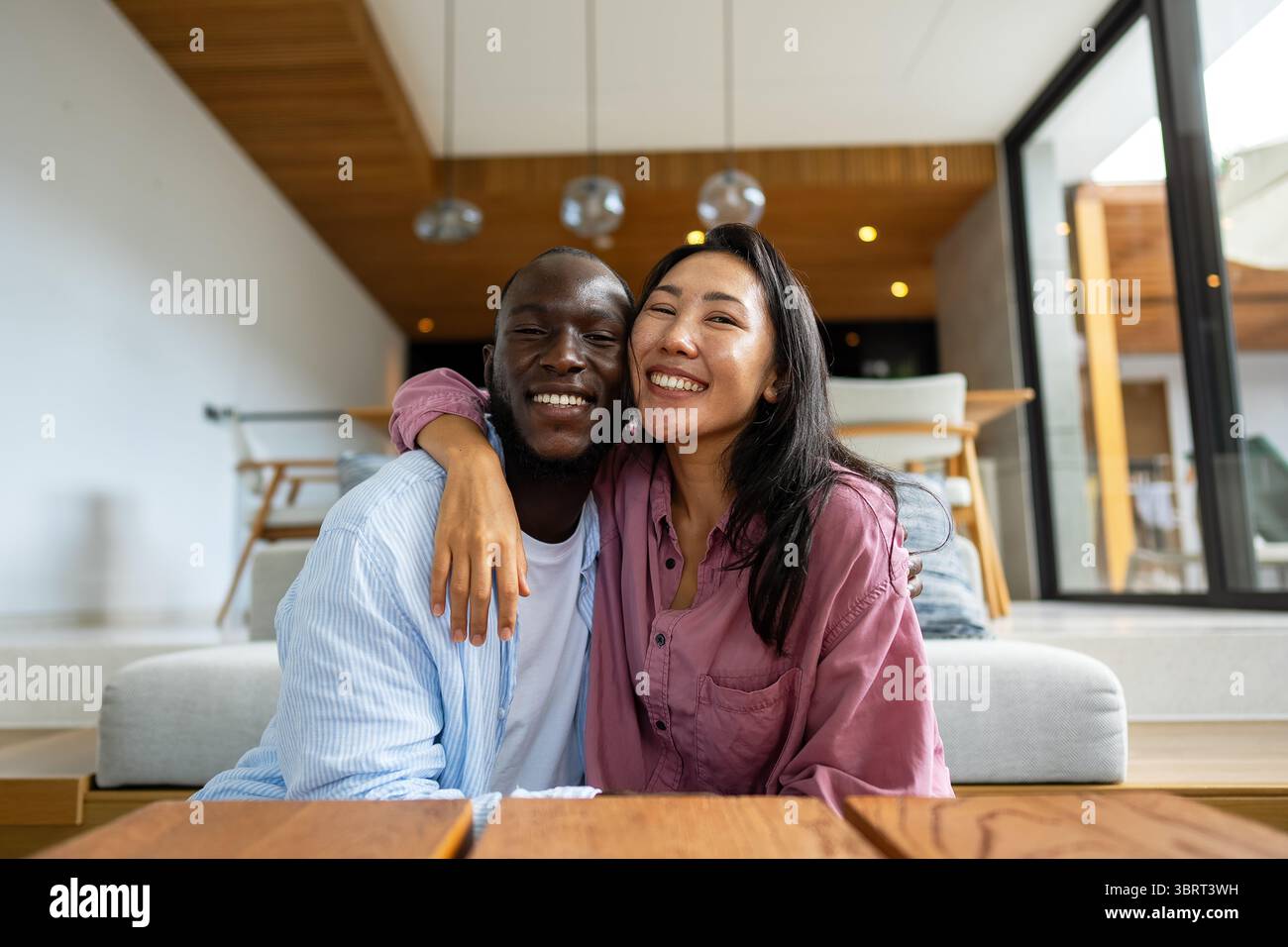 Happy and diverse couple sharing a joyful moment at home, embracing and ...