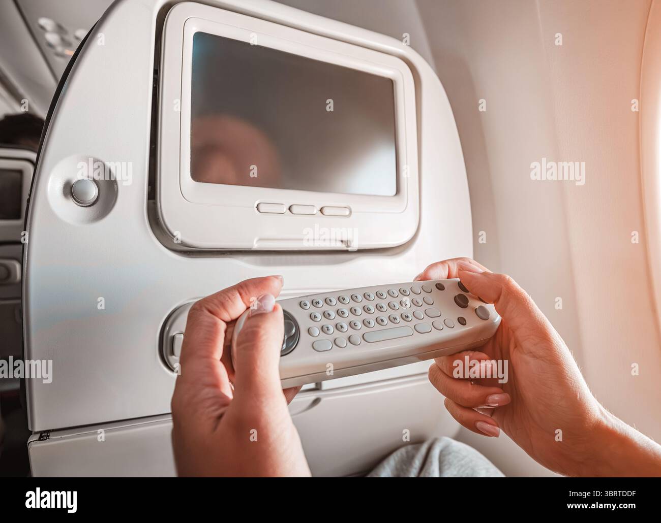 Passenger using remote control to navigate entertainment system during ...
