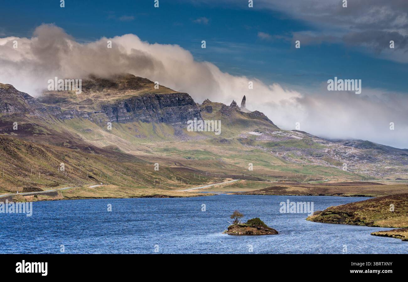 The Old Man of Storr appears between the clouds, seen over Loch Fada ...