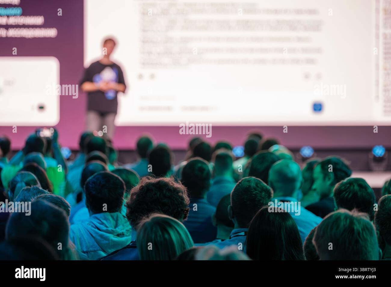 Large audience watching speaker deliver presentation on stage with ...
