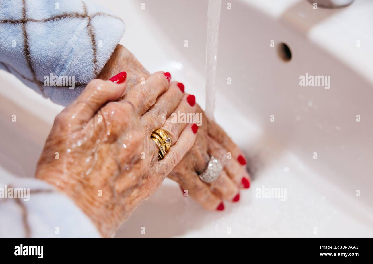 Elderly woman rinsing hands under faucet after washing Stock Photo - Alamy