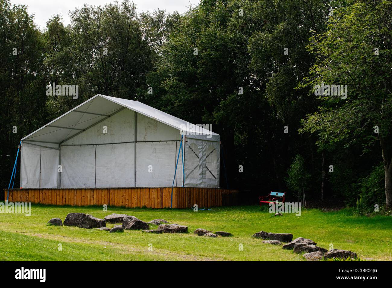 Temporary outdoor stage and seating amidst a lush green landscape in ...