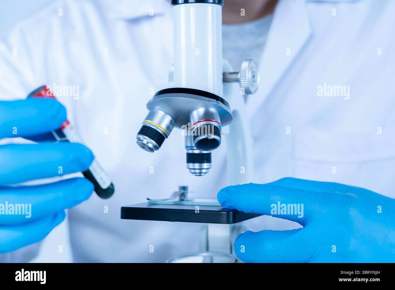 Scientist analyzing blood sample under microscope in laboratory ...