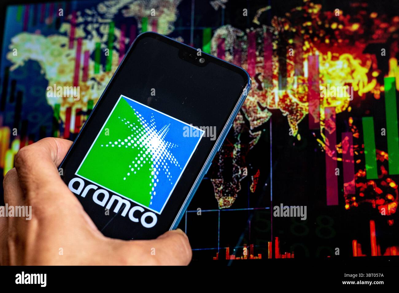 The Aramco logo displayed on a phone screen against a world map and ...