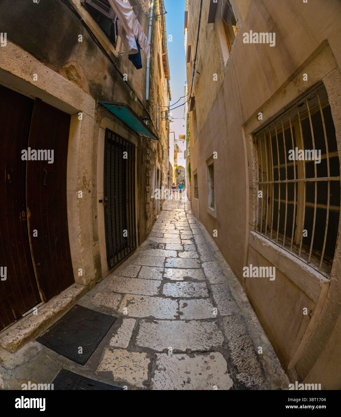 Split, Croatia - September 8th 2023: Two tourists walk down a narrow ...