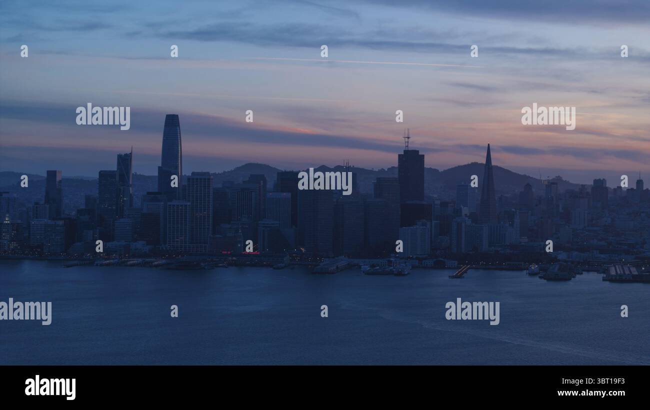 Aerial view of the city skyline is silhouetted against the fading light ...
