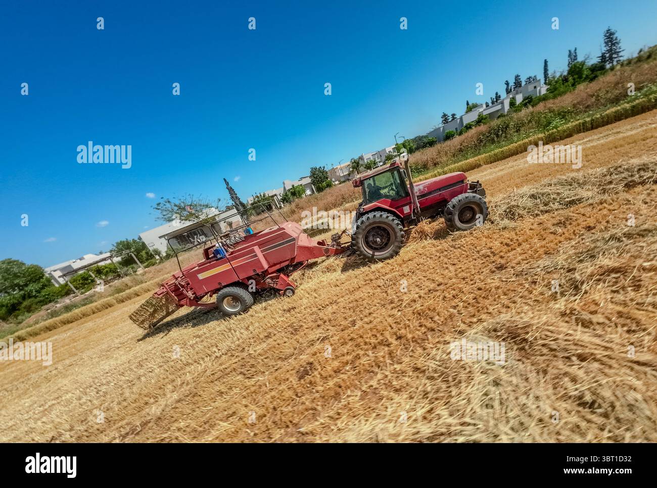 Aerial view of a vibrant red tractor and baler stands out against the ...