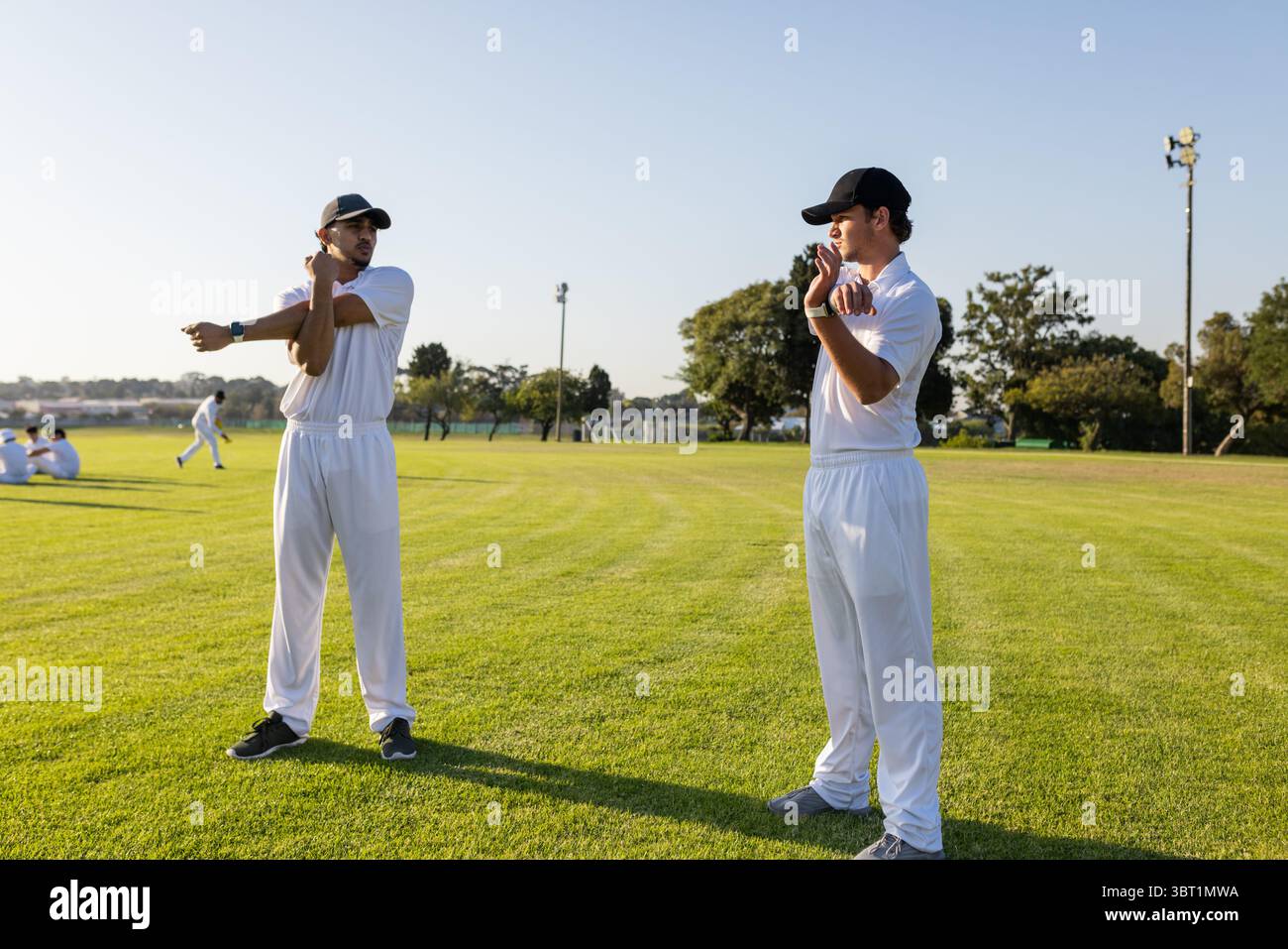 Diverse male teammates stretching arms across chest wearing white ...