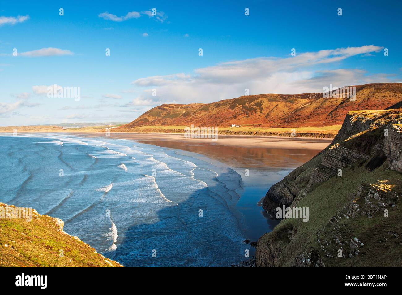 A sweeping view of Rhossili bay, Wales.. The ocean waves, bordered by ...