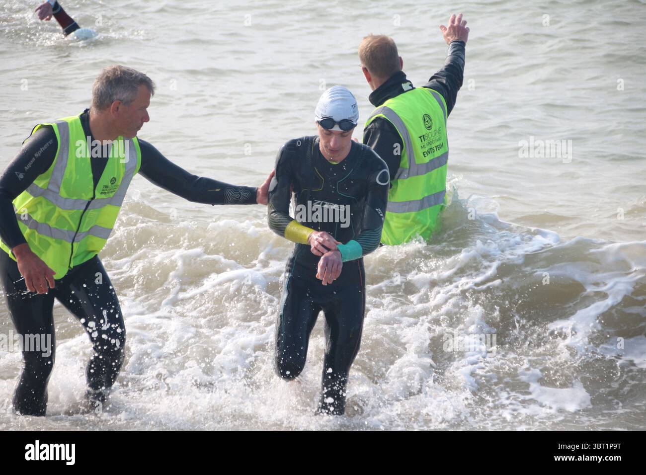 male triathlete helped from sea by race volunteers after swim leg of ...