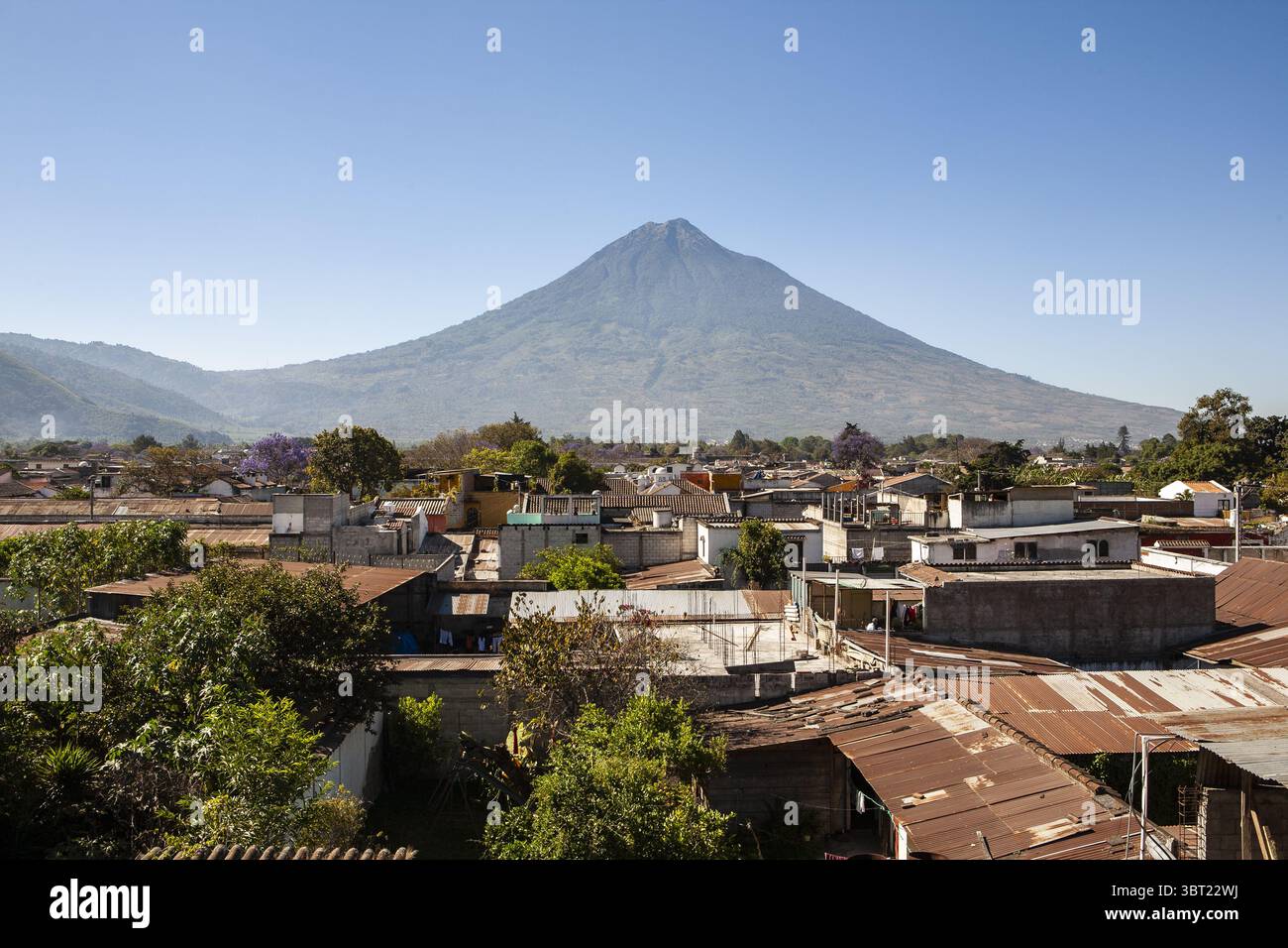 Aerial view of rustic rooftops cascade towards the looming Volcán de ...