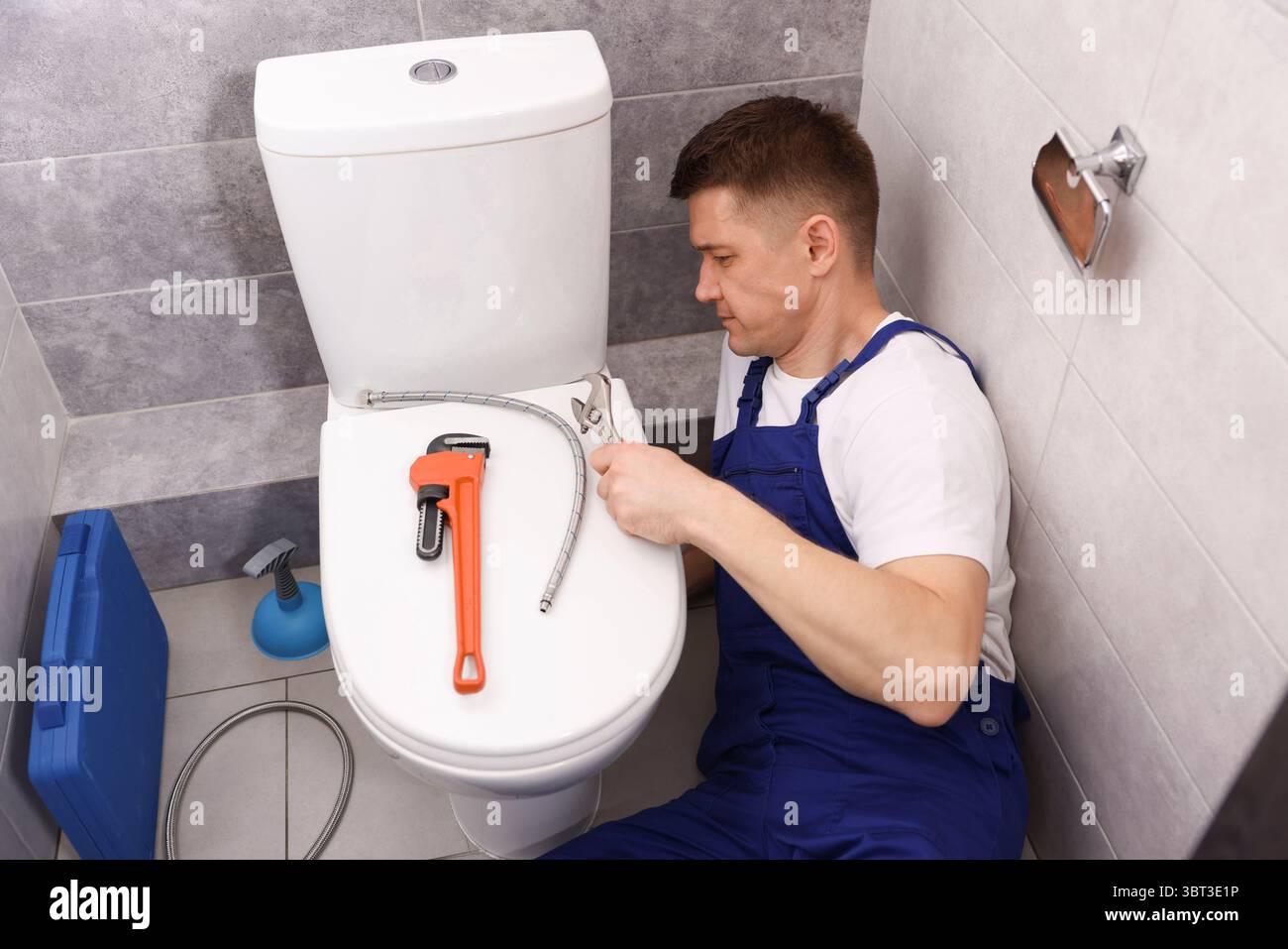 Professional plumber fixing toilet bowl in restroom Stock Photo - Alamy