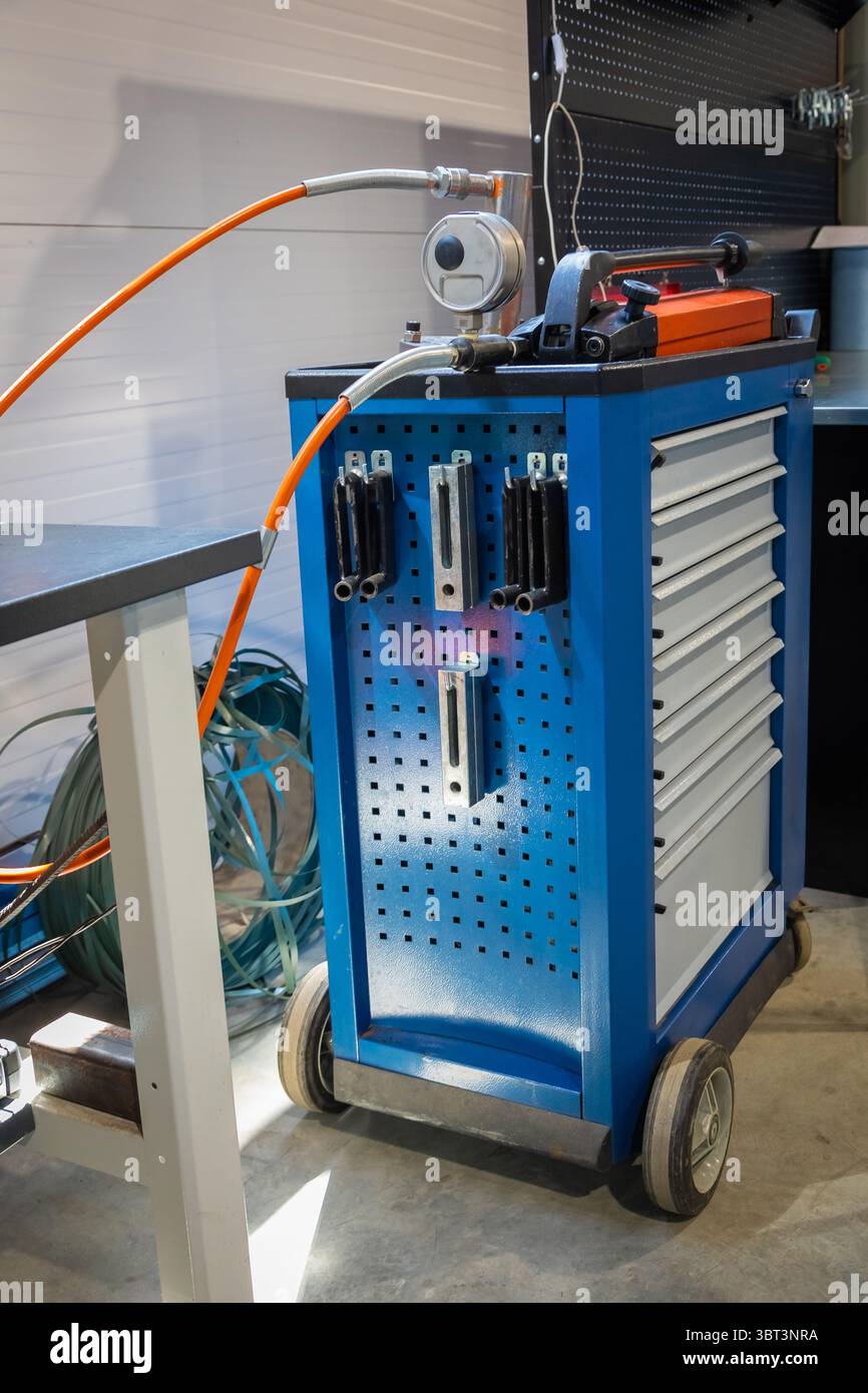 Blue metal rolling tool cart with hydraulic hoses, pressure gauge, and ...