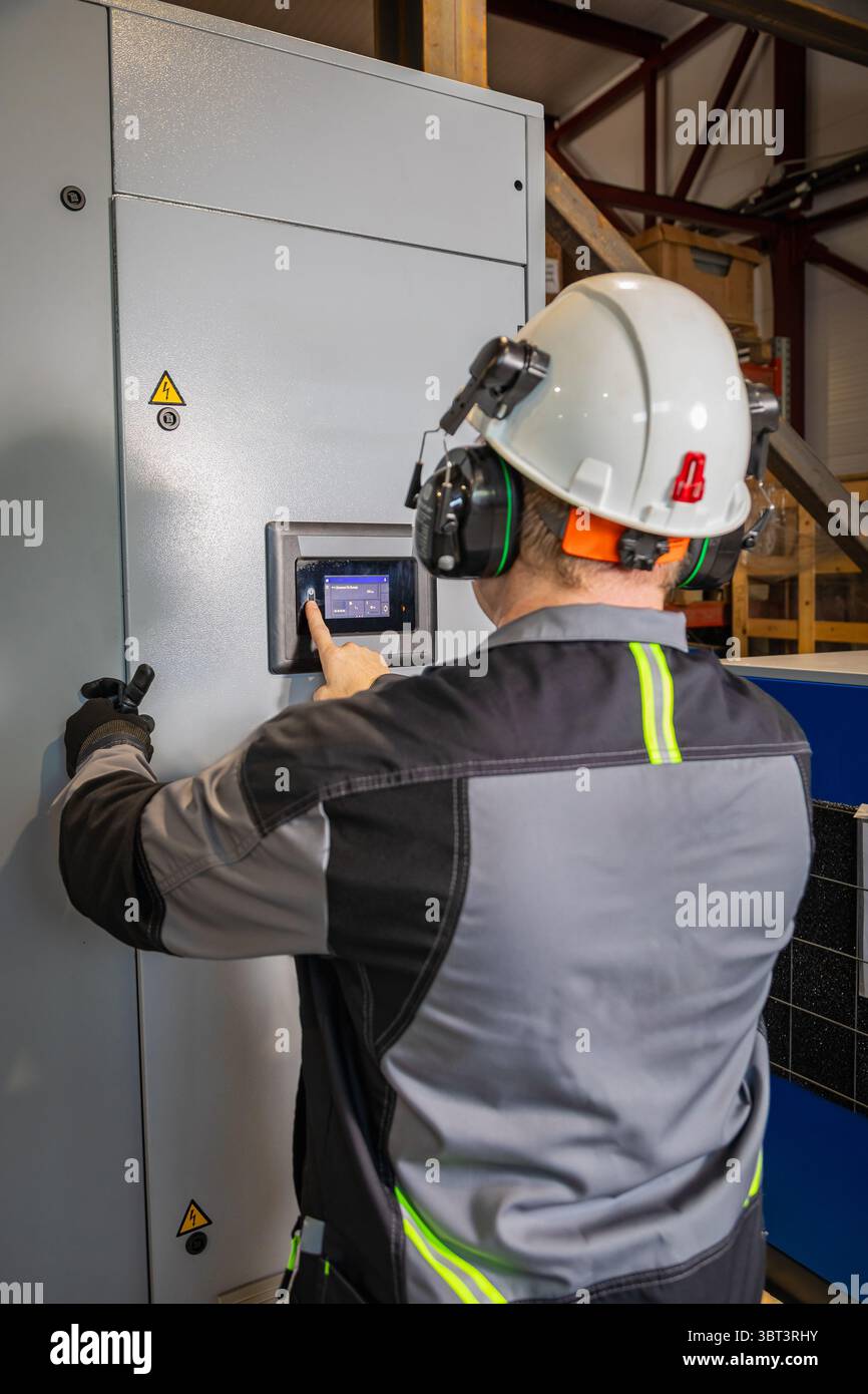 Industrial technician operating a control panel, wearing safety helmet ...