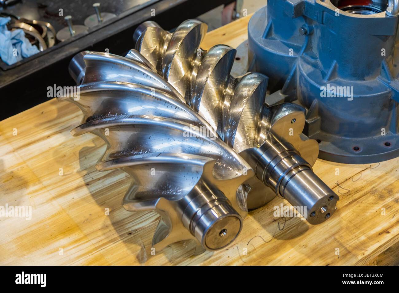 Brand new screw compressor rotor lies on a wooden workbench, showcasing ...