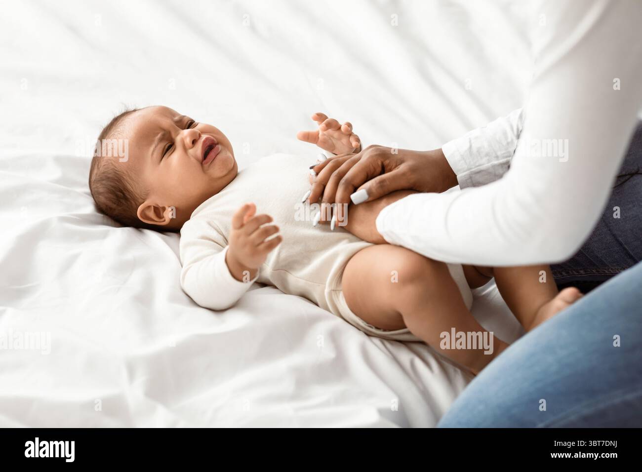 Black mother doing belly massage for crying infant Stock Photo - Alamy