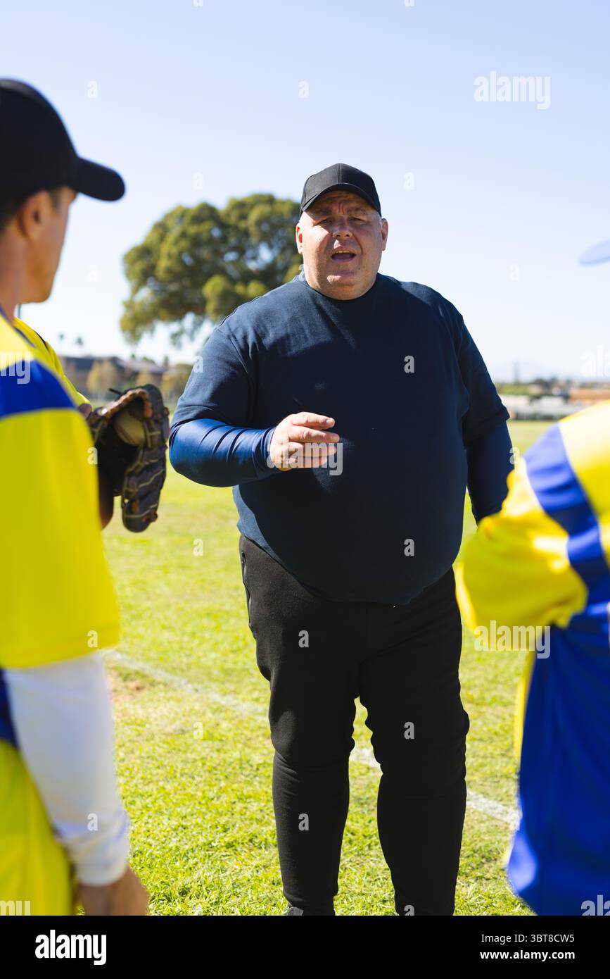 White baseball coach with male players coaching on baseball field with ...
