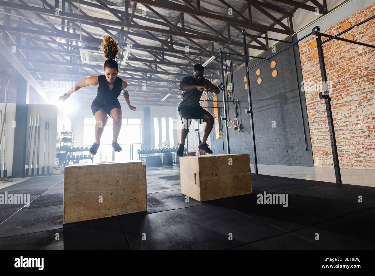 Diverse workout partners in athletic wear jumping onto wooden ...