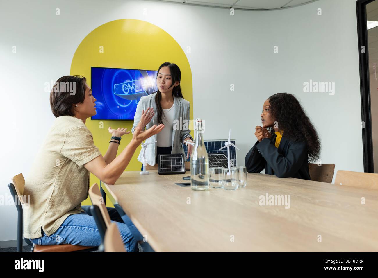 Diverse coworkers presenting solar panel and wind turbine models at ...