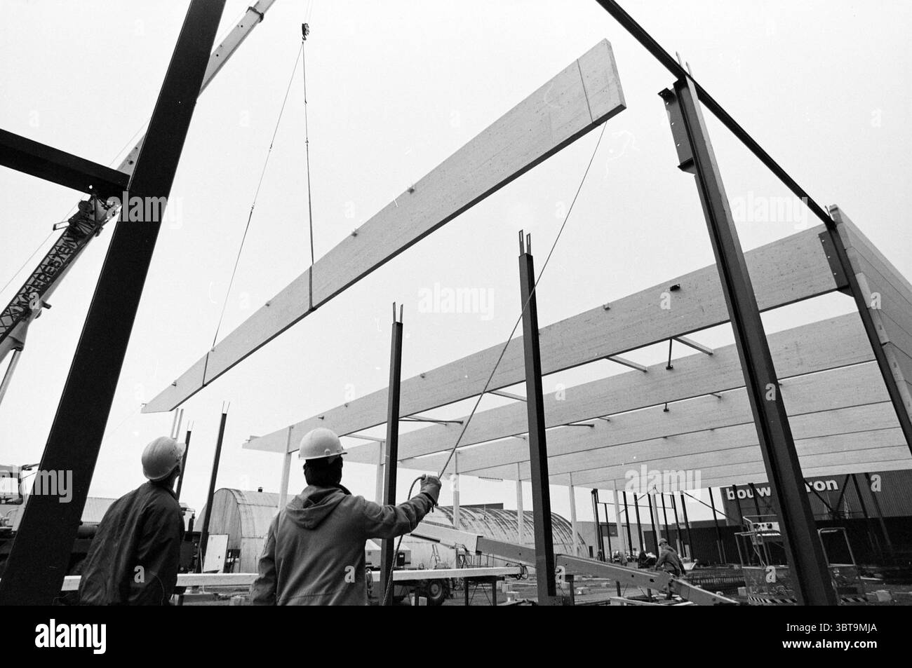 Two workers maneuver large structural beams hi-res stock photography ...
