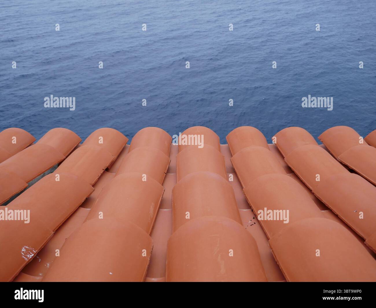 View out window over clay roof tiles with ocean waves below Stock Photo ...