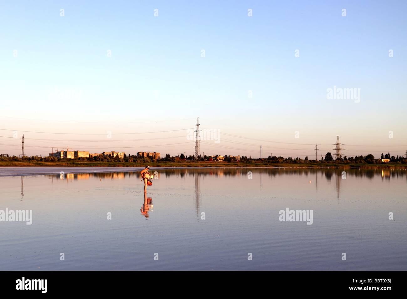 A woman sunbathes in the salty water of Kuyalnik Estuary at sunset. The ...