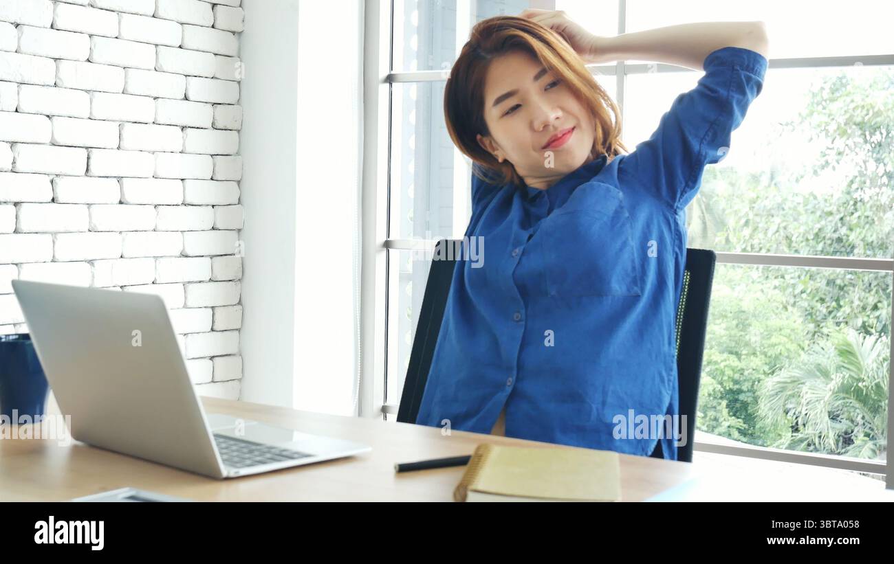Woman streching arm raised sitting incorrect position home office desk ...