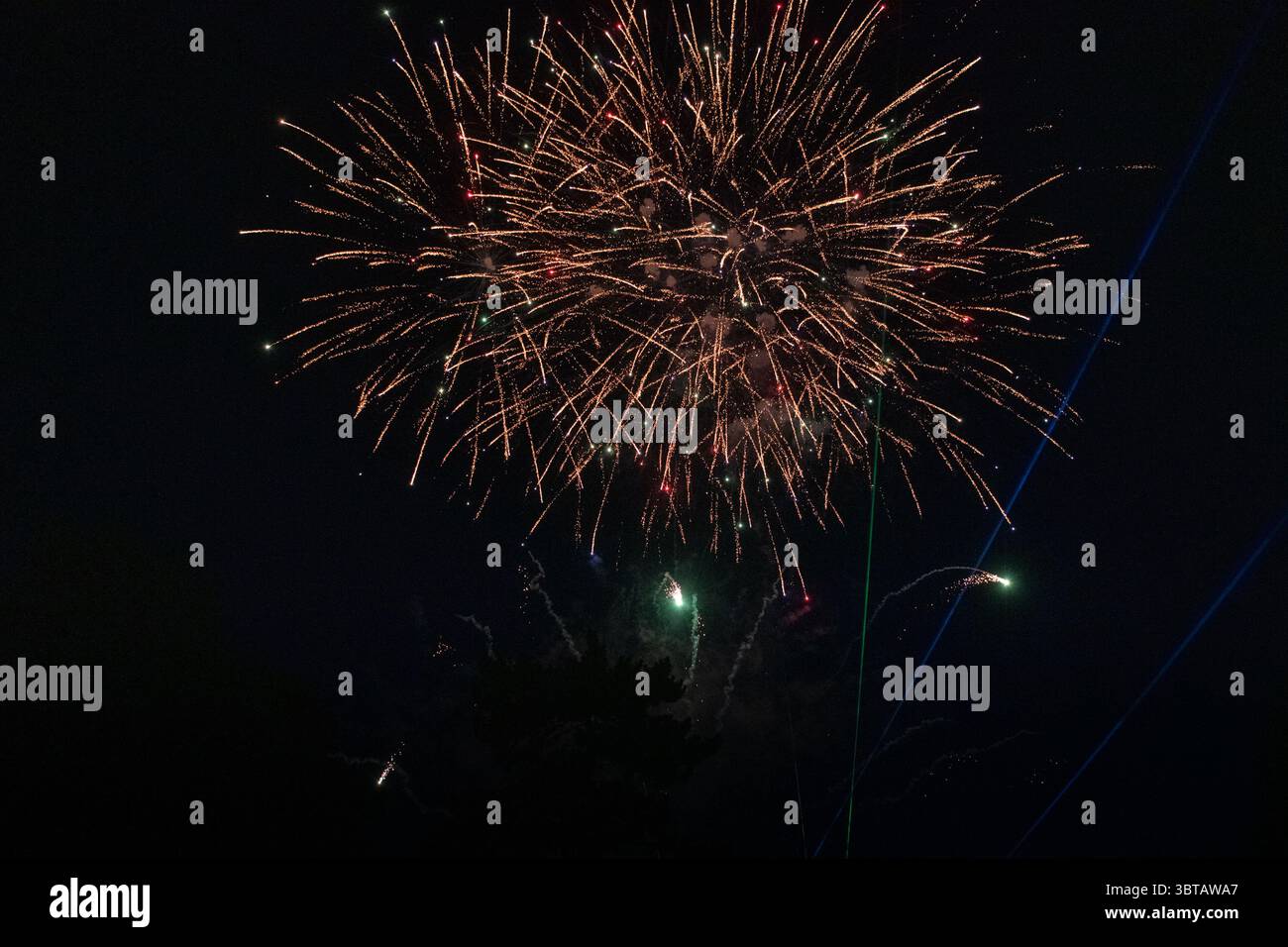 A large firework lights up the night sky, filling it with brilliant ...