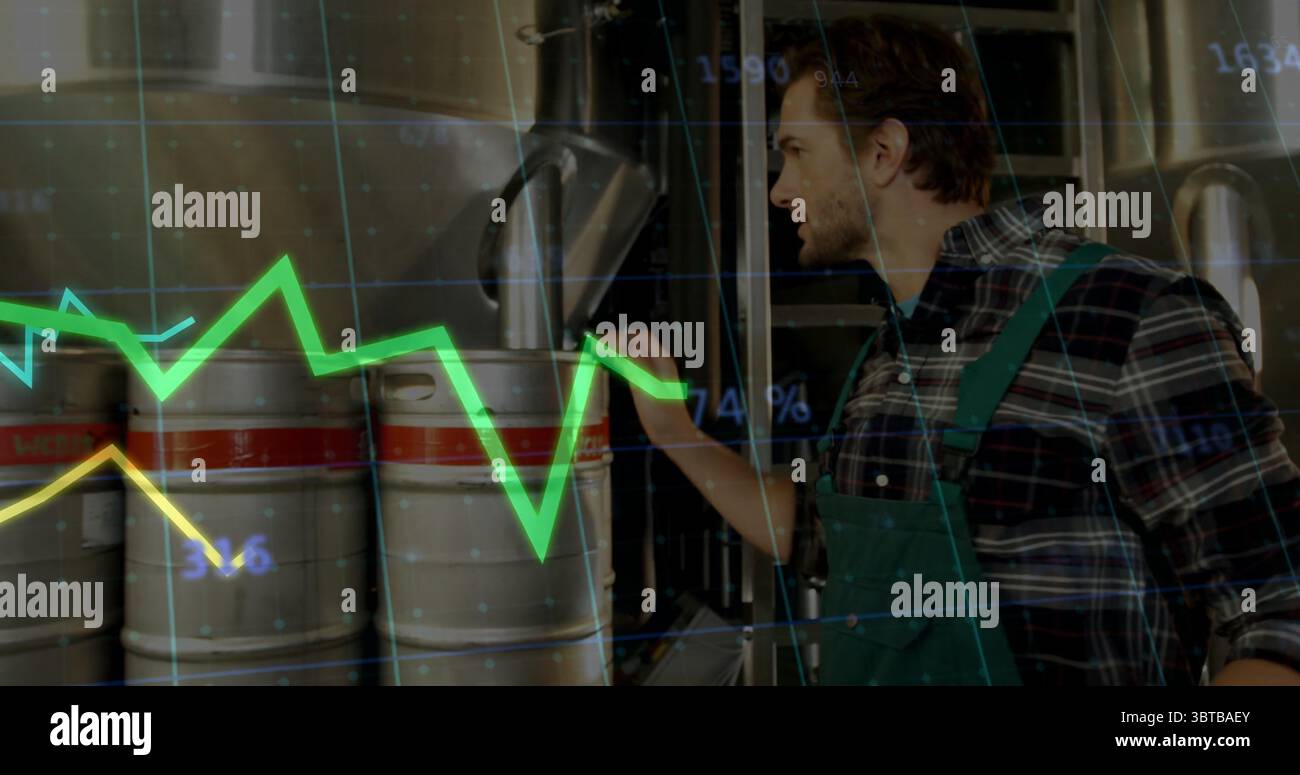 Worker in brewery wearing green apron analyzing brew, kegs and tanks ...