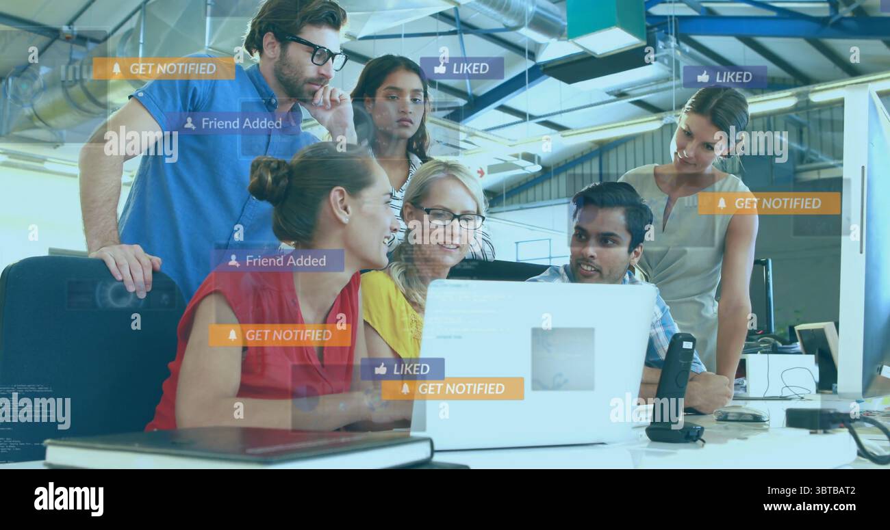 Collaborating team viewing laptop screens in open-plan office, with ...