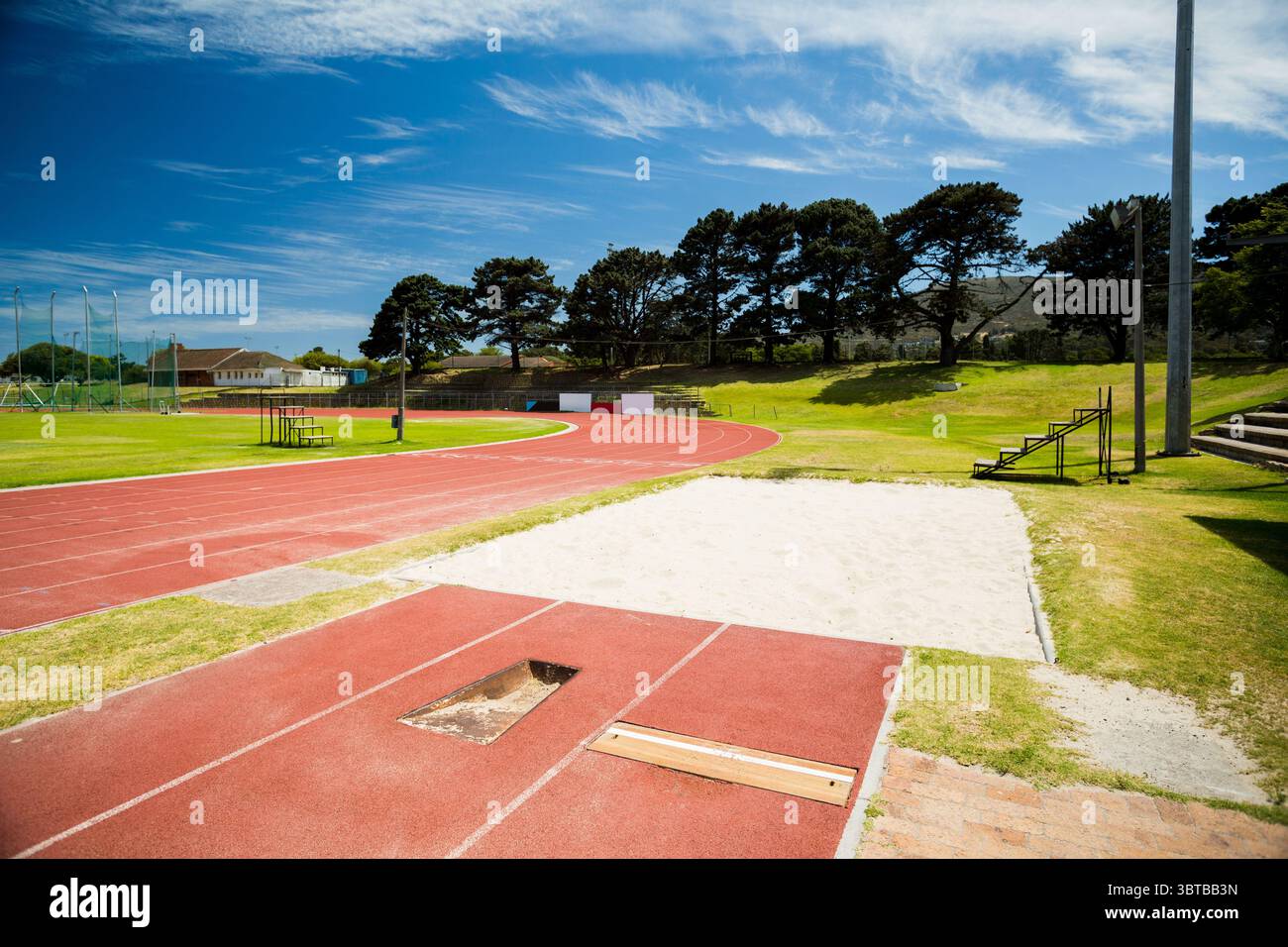 Long jump runway and sandpit are stretching across grassy field in flat ...
