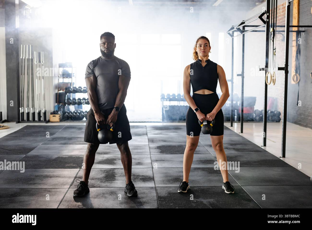 Diverse workout partners holding kettlebells on rubber mat floor at ...