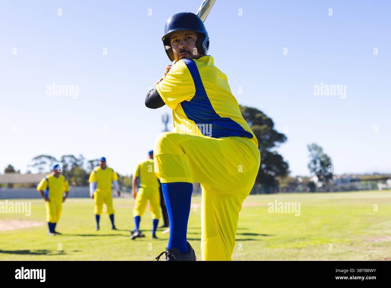 Male cricket team in yellow-and-blue uniforms taking batting stance on ...