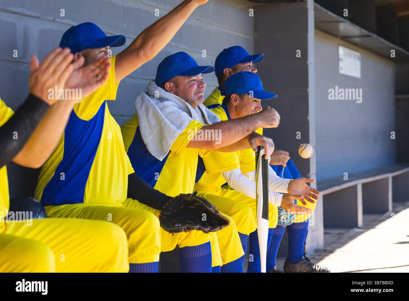 Male baseball teammates cheering and passing baseball with bat, glove ...