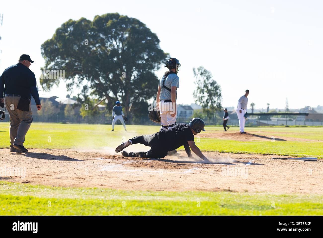 African American male sliding into home plate kicking dirt while ...