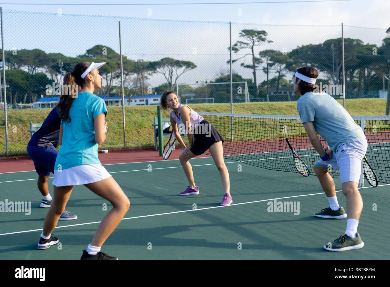 Diverse group of tennis players standing in ready stance on outdoor ...