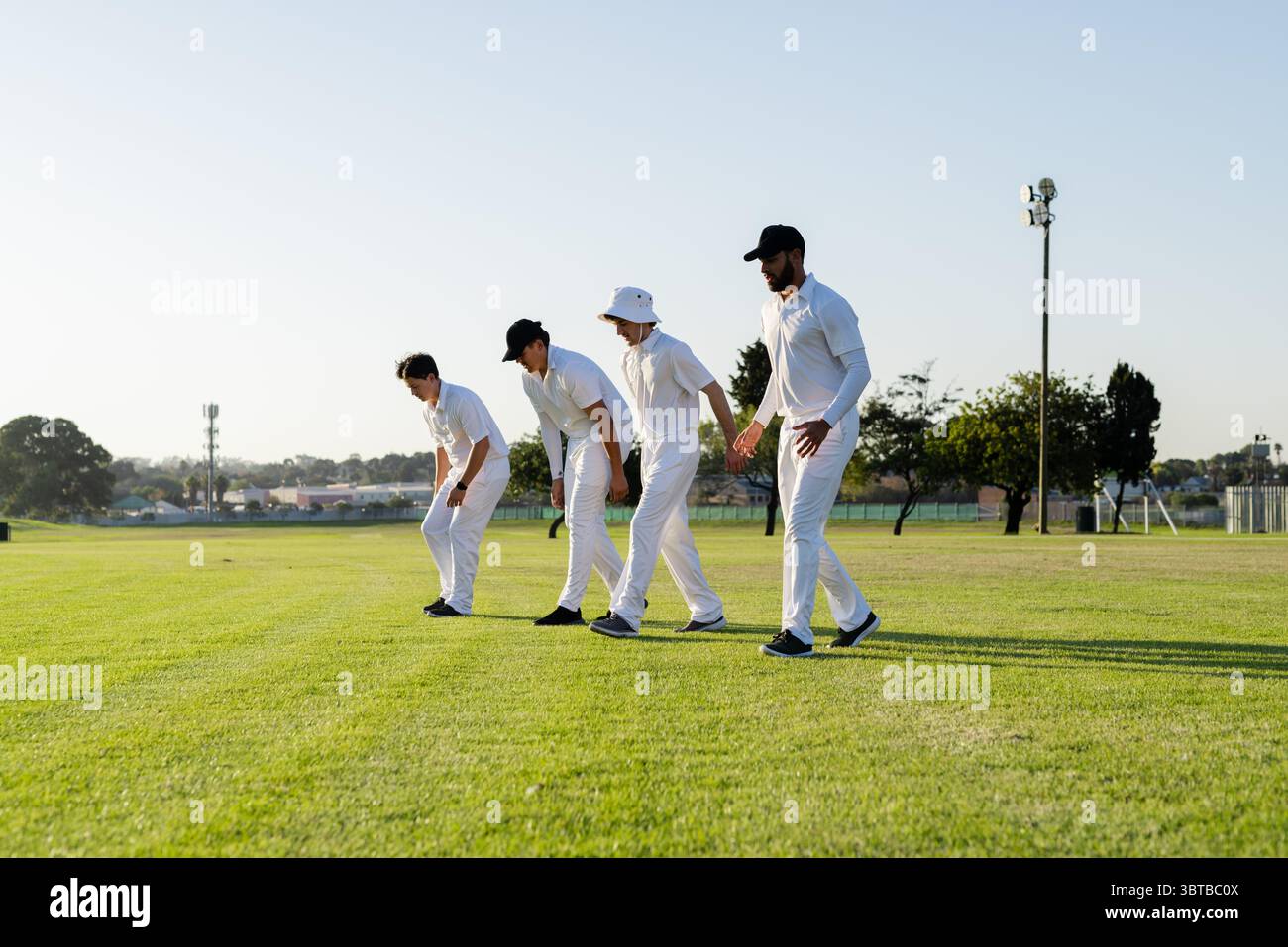 Diverse male cricket teammates standing in line wearing white uniforms ...