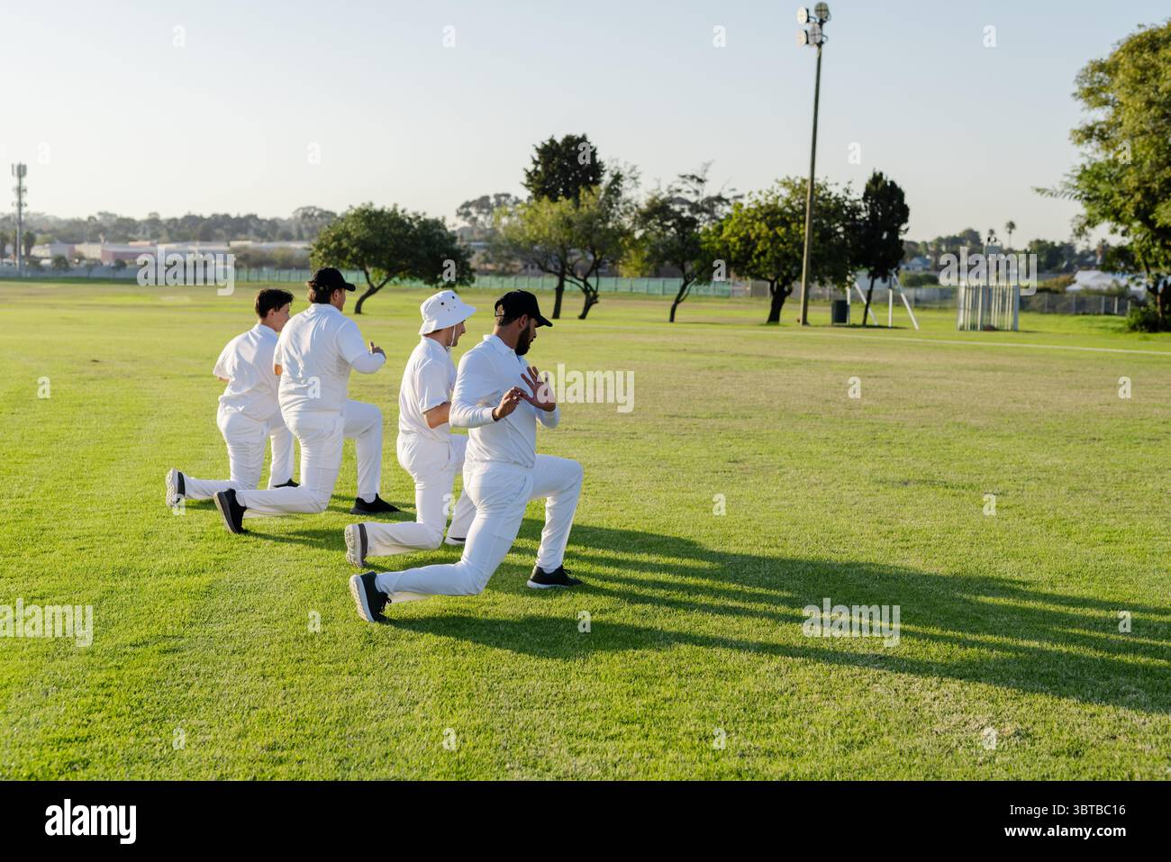 Diverse male cricket teammates performing forward lunges on cricket ...