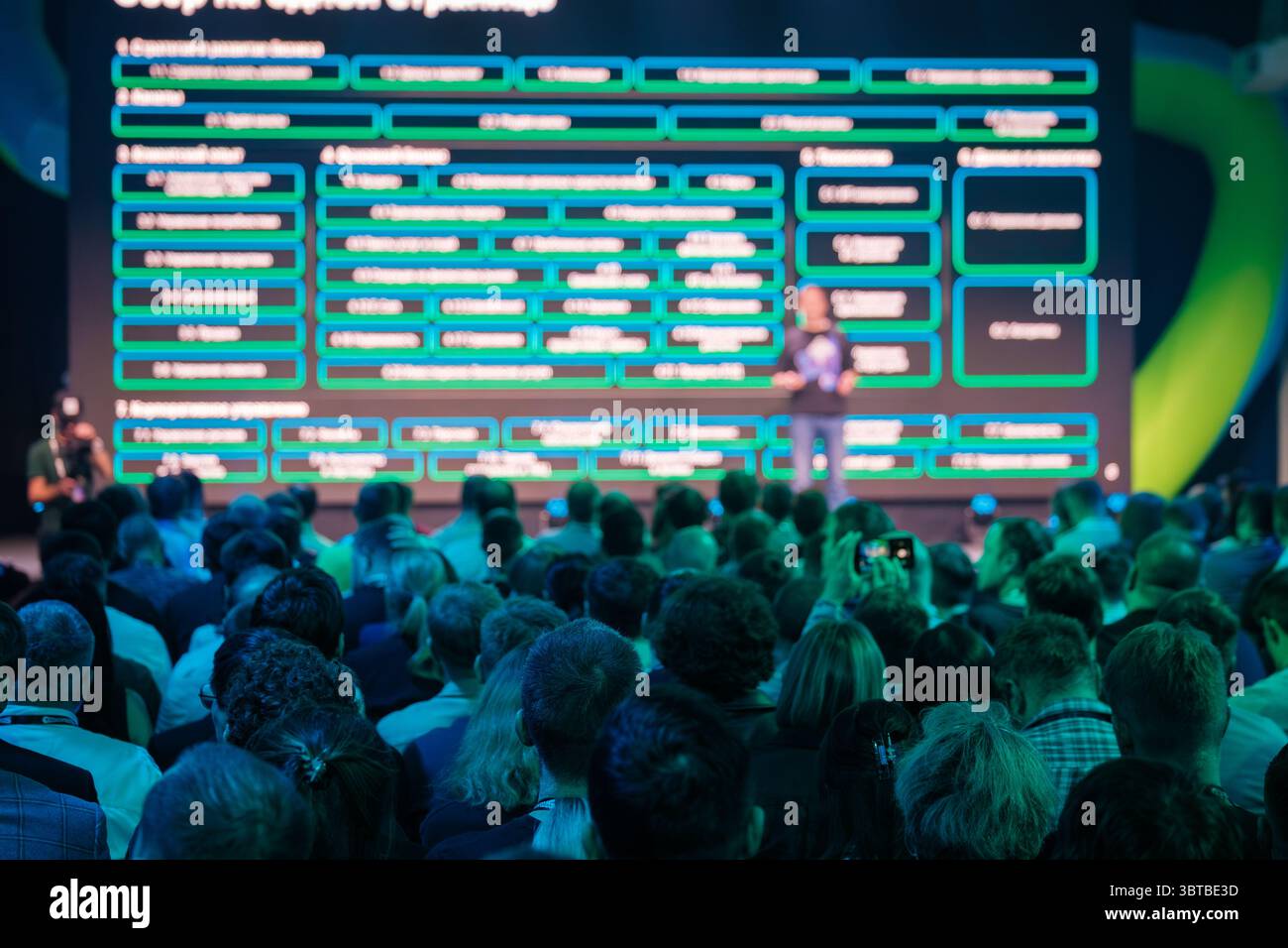 Blurred crowd attending a professional conference with a speaker on ...