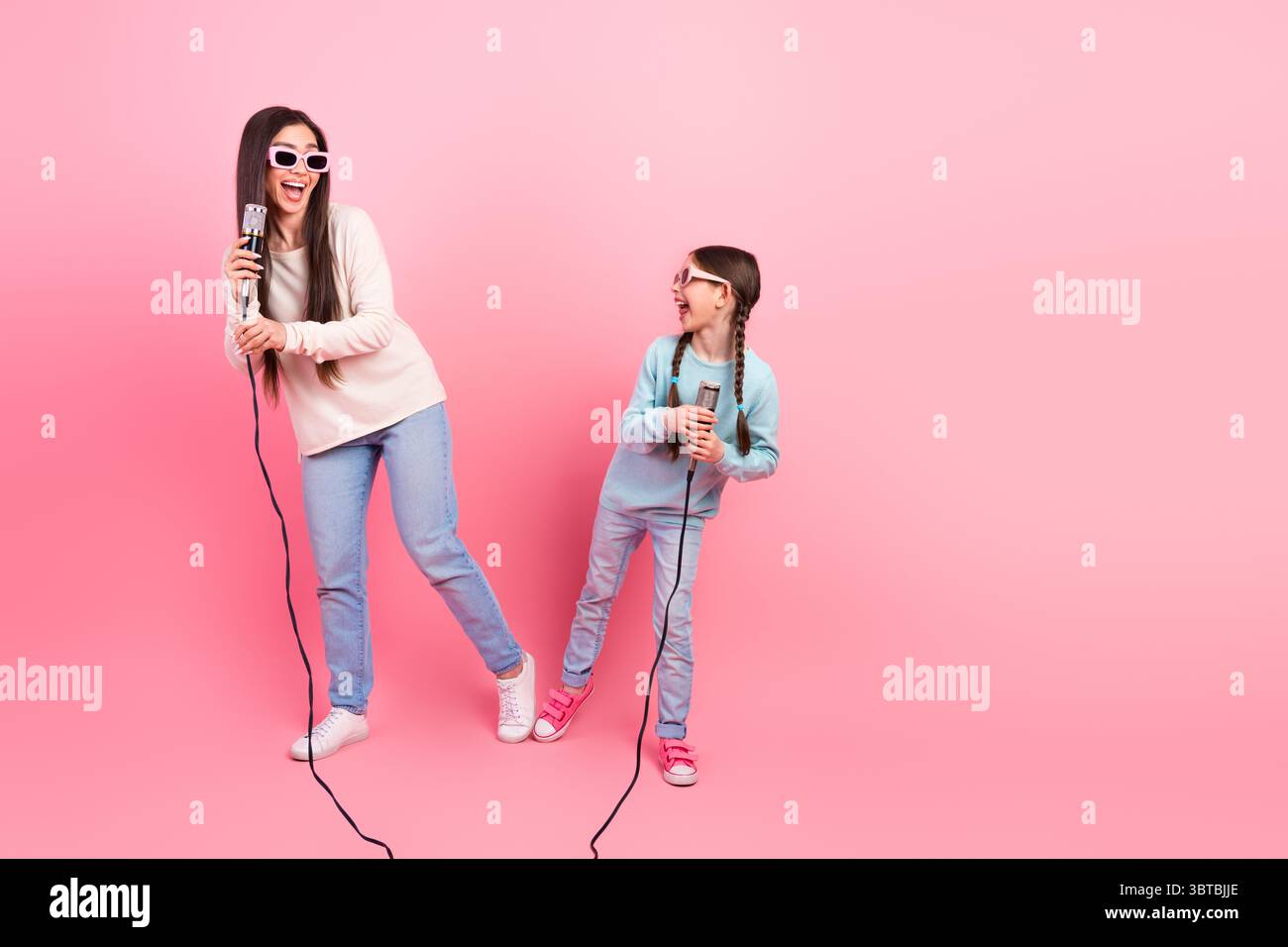 Mother and daughter singing karaoke together in a cheerful moment on a ...