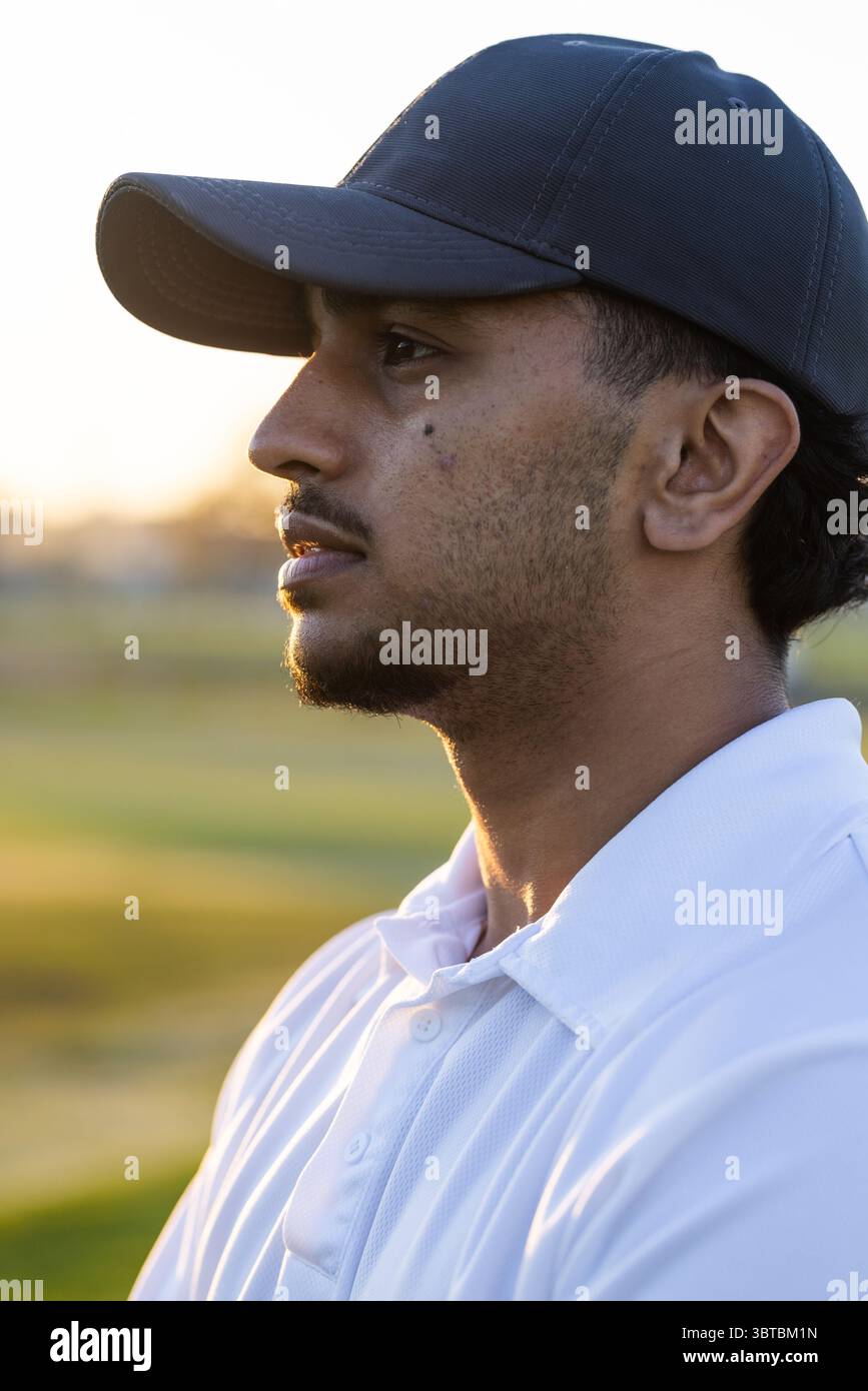Indian man standing in field at sunset wearing black baseball cap and ...