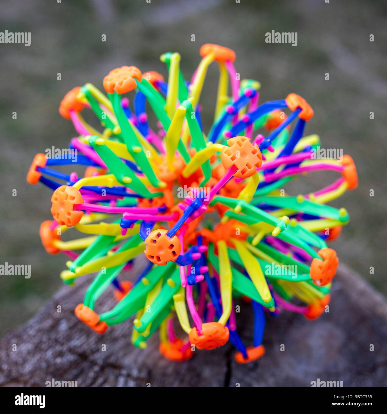 A close-up of a colorful expanding ball toy, known as a Hoberman sphere ...