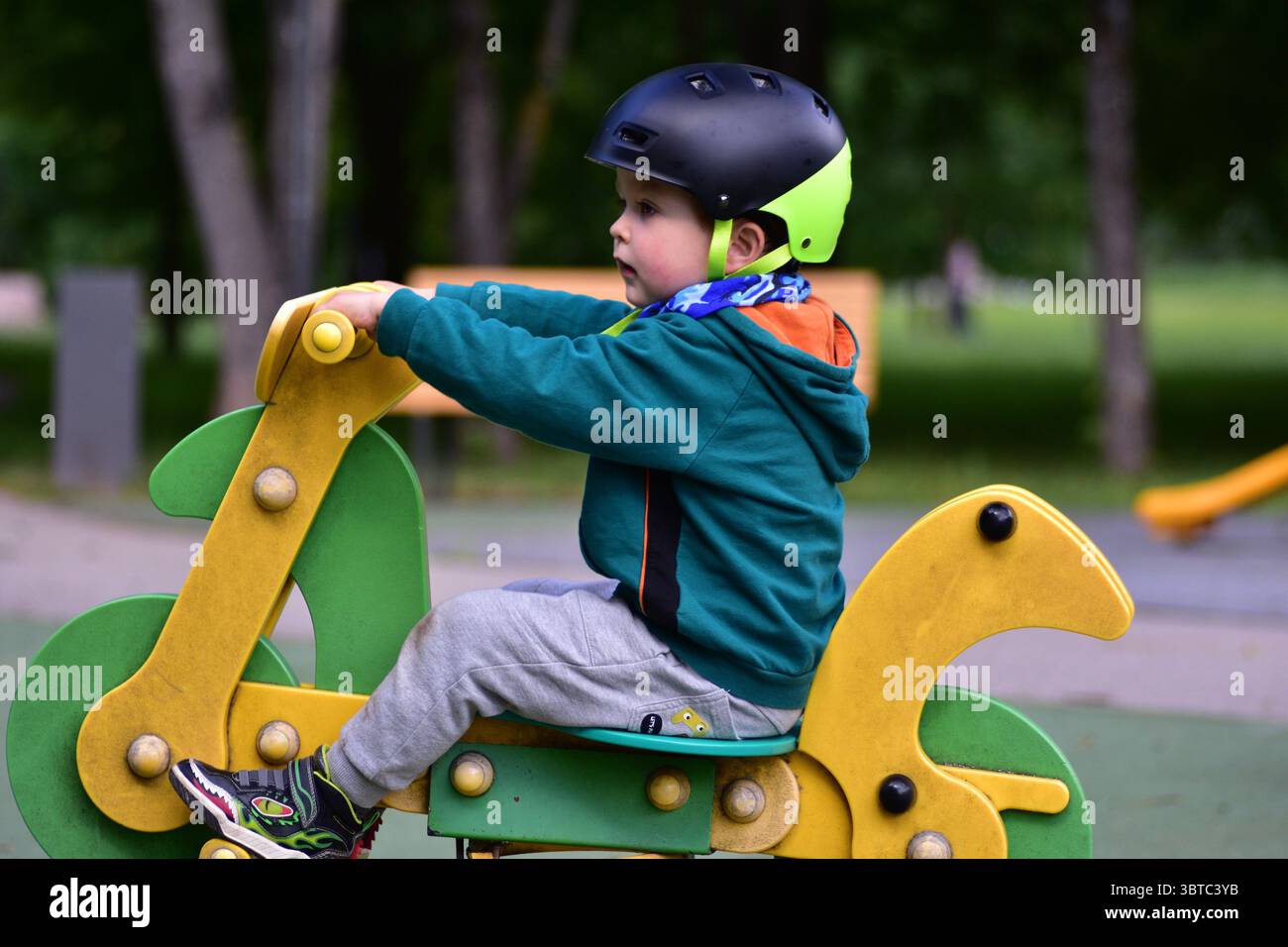 Boy riding green and yellow spring rocker shaped like a motorcycle at ...
