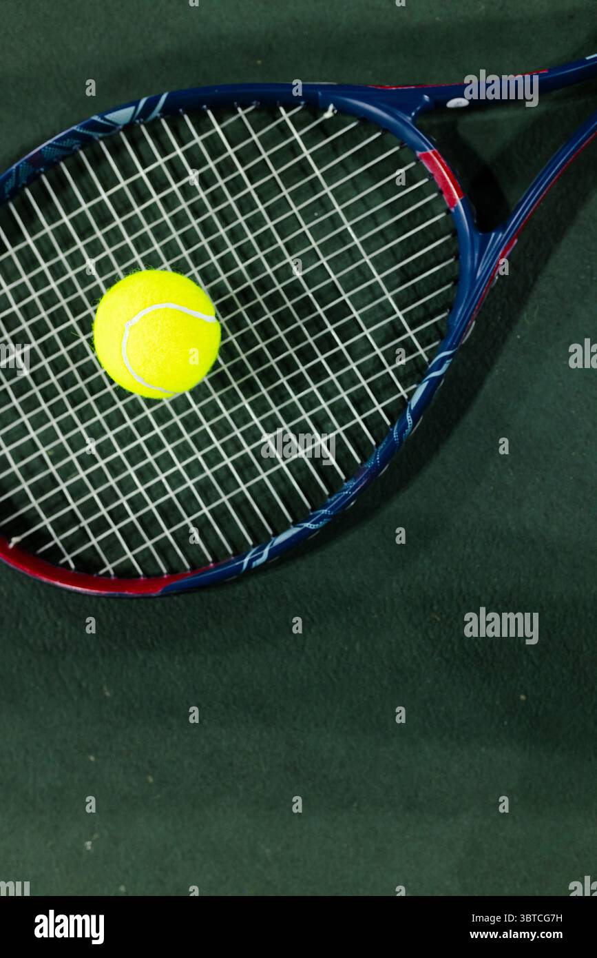 Tennis racket resting on dark green court while yellow ball sitting in ...