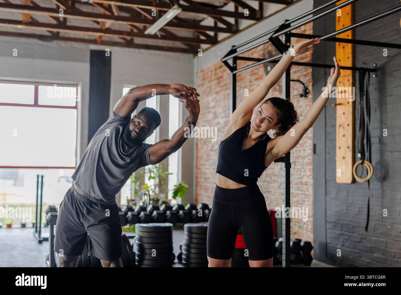 Diverse trainer and client practicing stretching in sportswear at ...