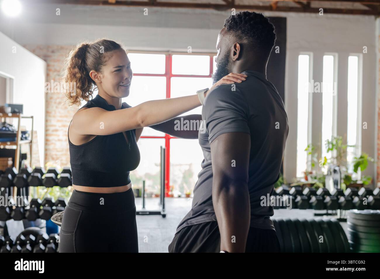 Female client and African American trainer practicing shoulder stretch ...