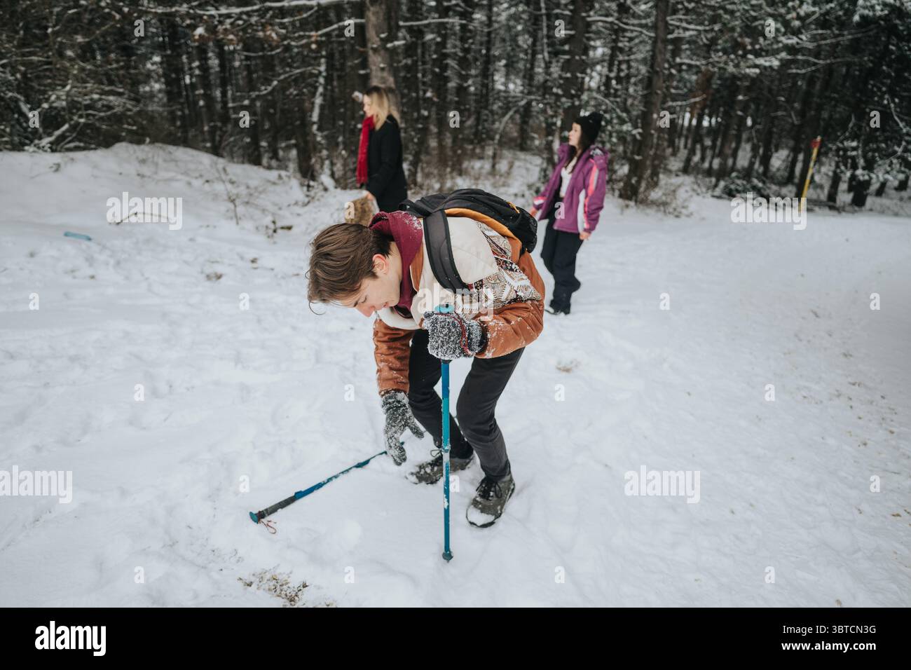 Group of people exploring a snowy forest trail during winter with ...